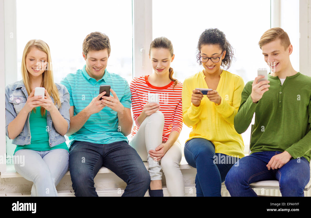 smiling students with smartphone texting at school Stock Photo - Alamy