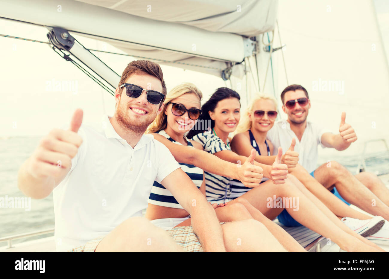smiling friends on yacht showing thumbs up Stock Photo - Alamy