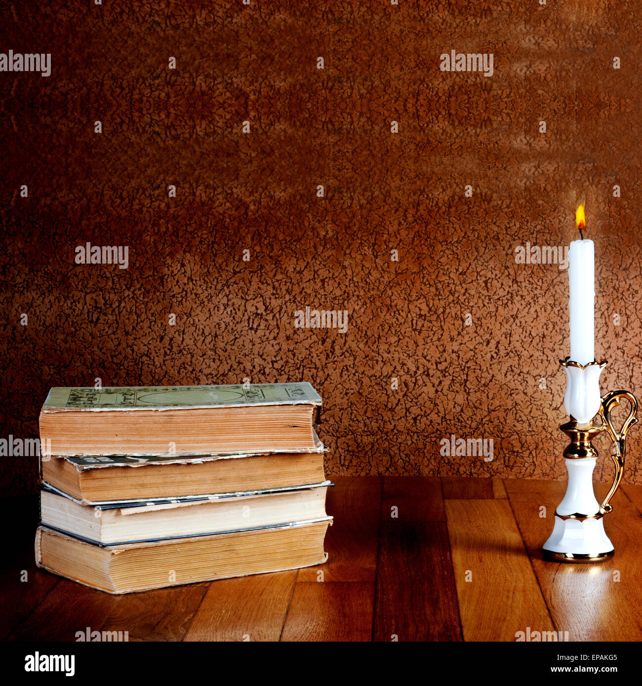 Old stack of books with candlestick and burning candle on the wooden ...