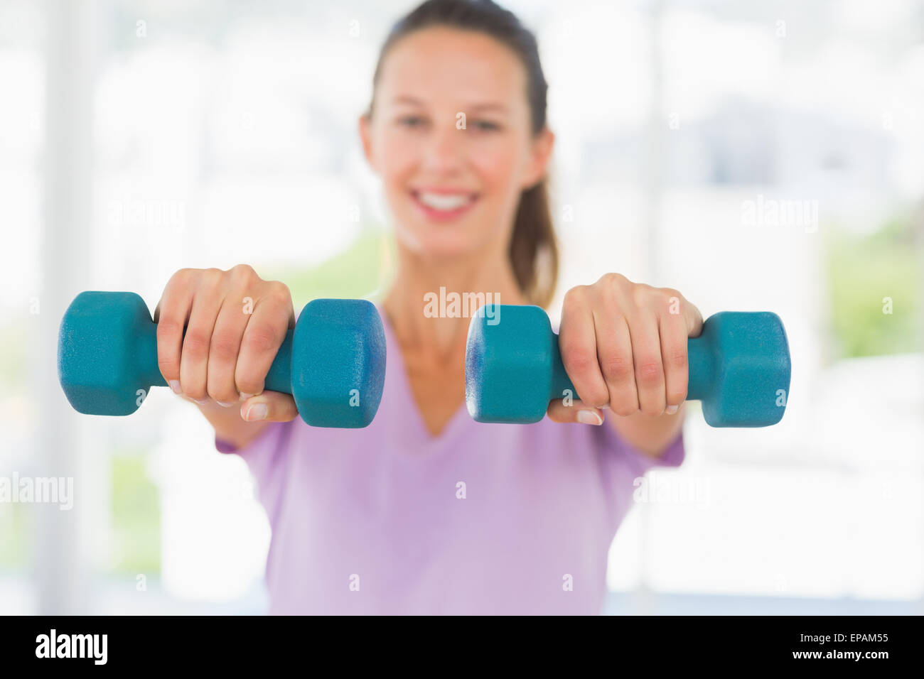 Smiling woman lifting dumbbell weights in a bright gym Stock Photo - Alamy