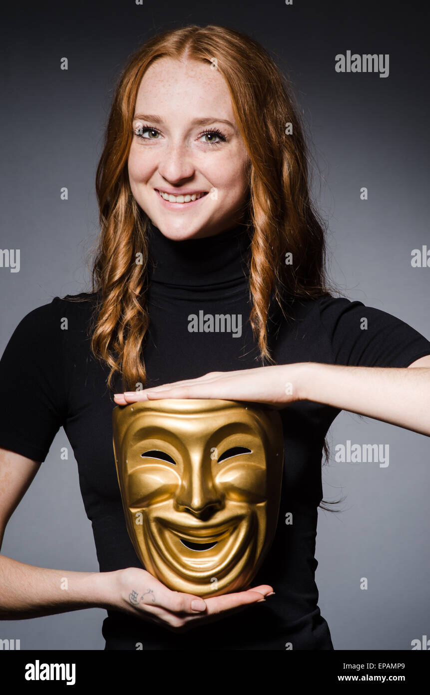 Redhead woman iwith mask in hypocrisy consept against grey background ...