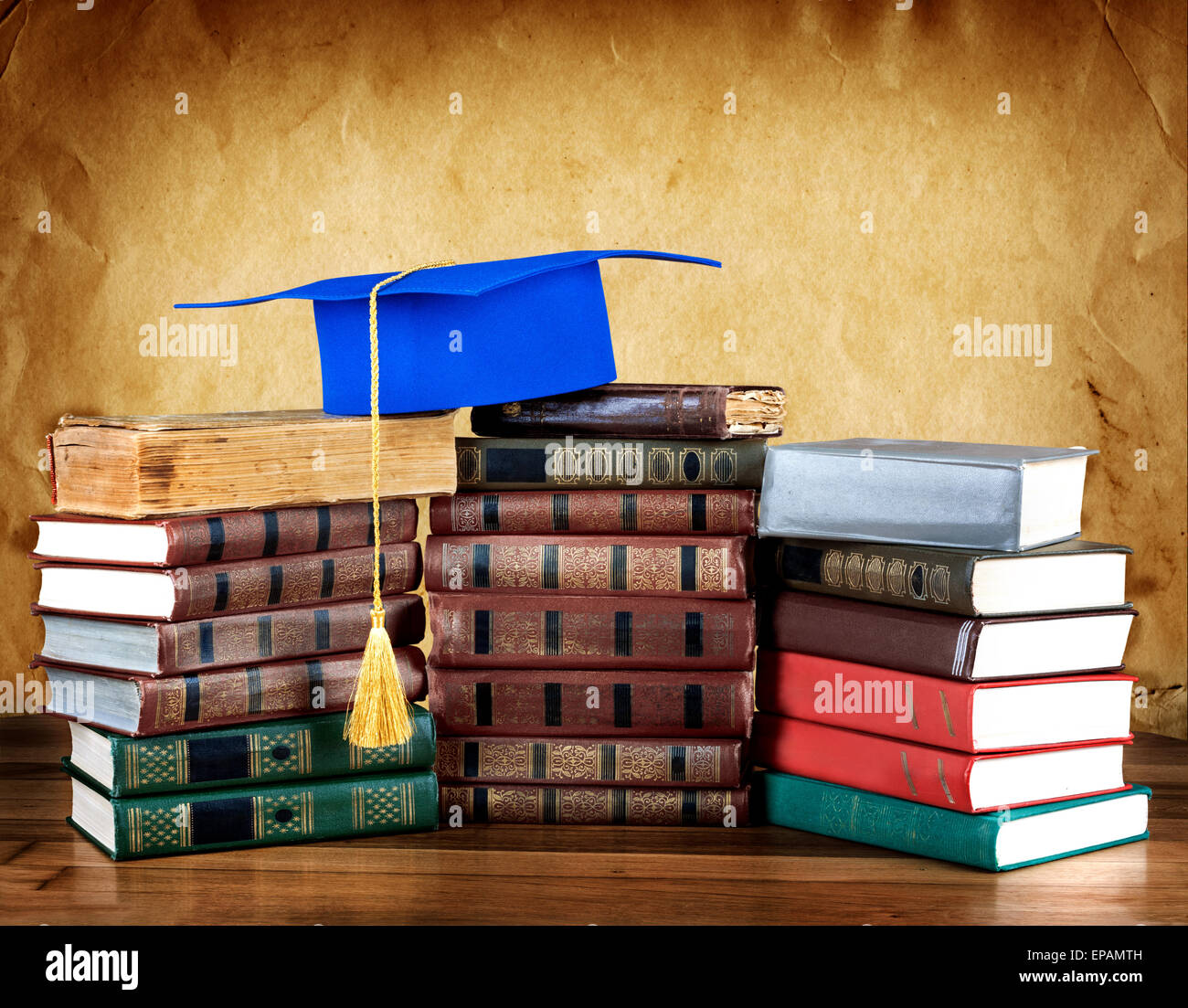 Graduation mortarboard on top of stack of books on abstract background ...