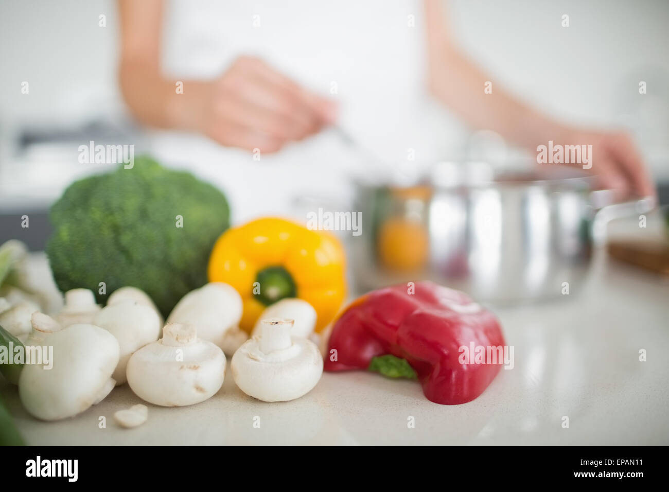 Vegetables with blurred woman preparing food in kitchen Stock Photo - Alamy
