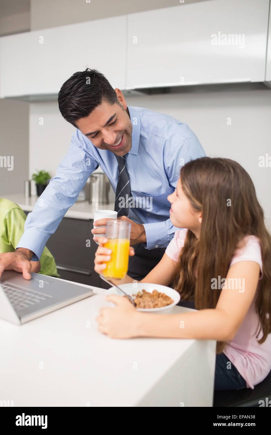 Father using laptop and kids having breakfast in kitchen Stock Photo ...