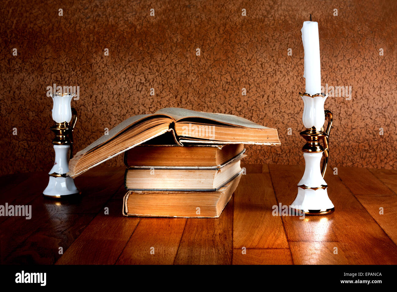 Old stack of books with candlestick and burning candle on the wooden ...