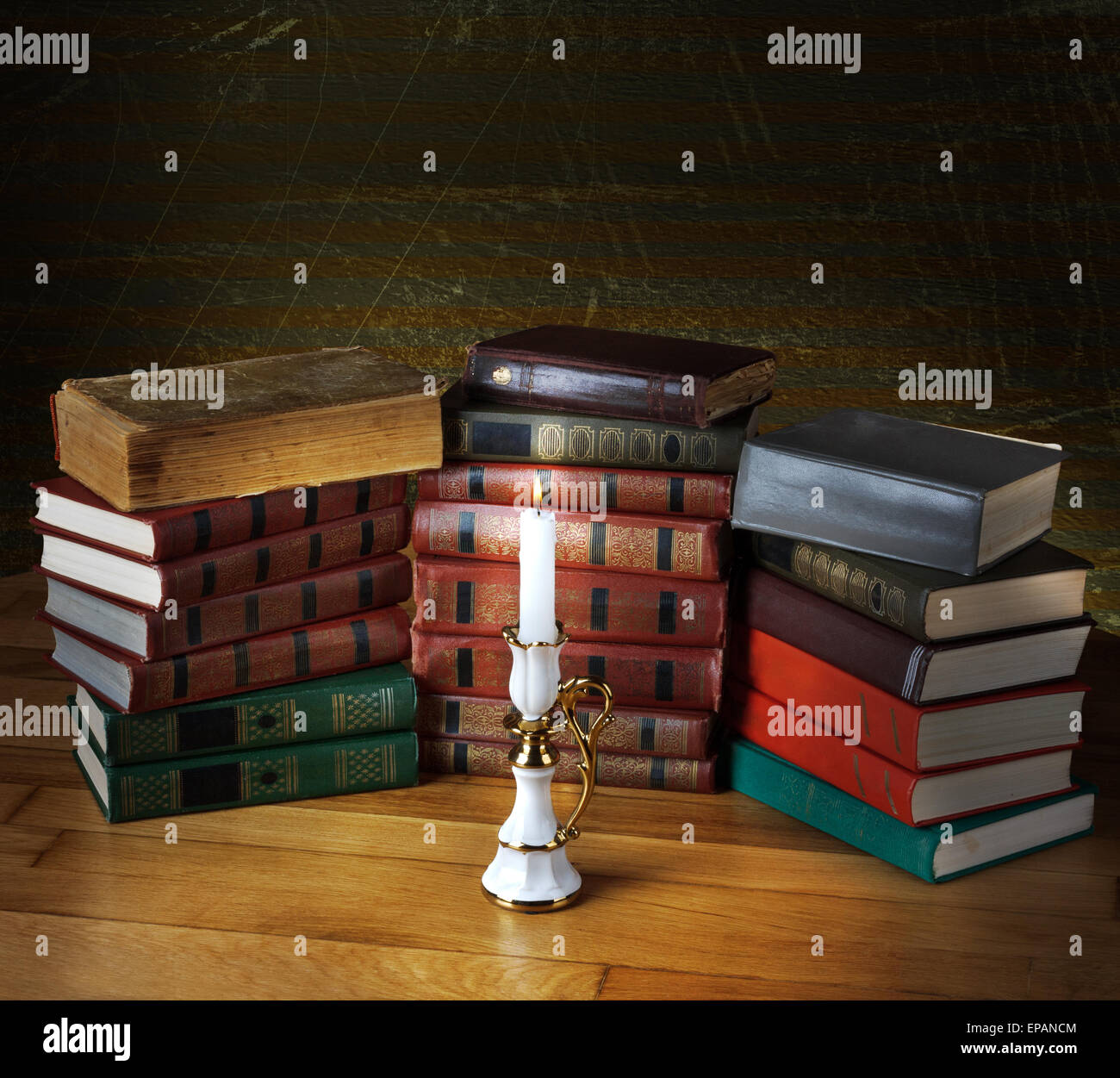 Old stack of books with candlestick and burning candle on the wooden ...