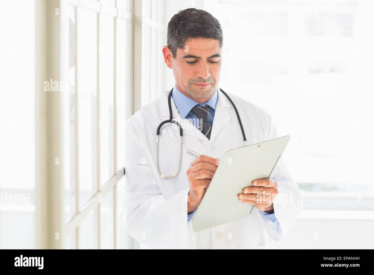 Male doctor writing on clipboard Stock Photo - Alamy