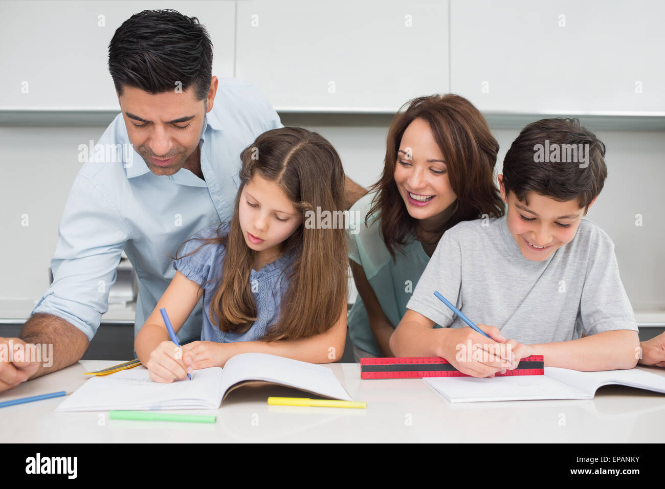Couple helping kids with their homework in kitchen Stock Photo - Alamy