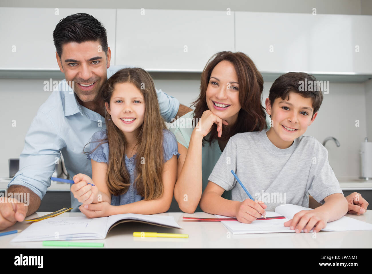 Smiling couple helping kids with homework at home Stock Photo - Alamy