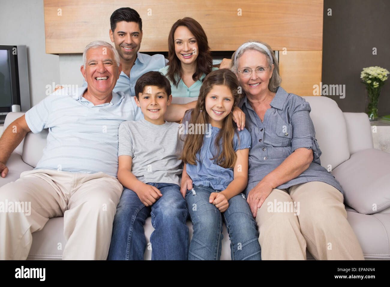 Portrait of smiling extended family on sofa in living room Stock Photo ...