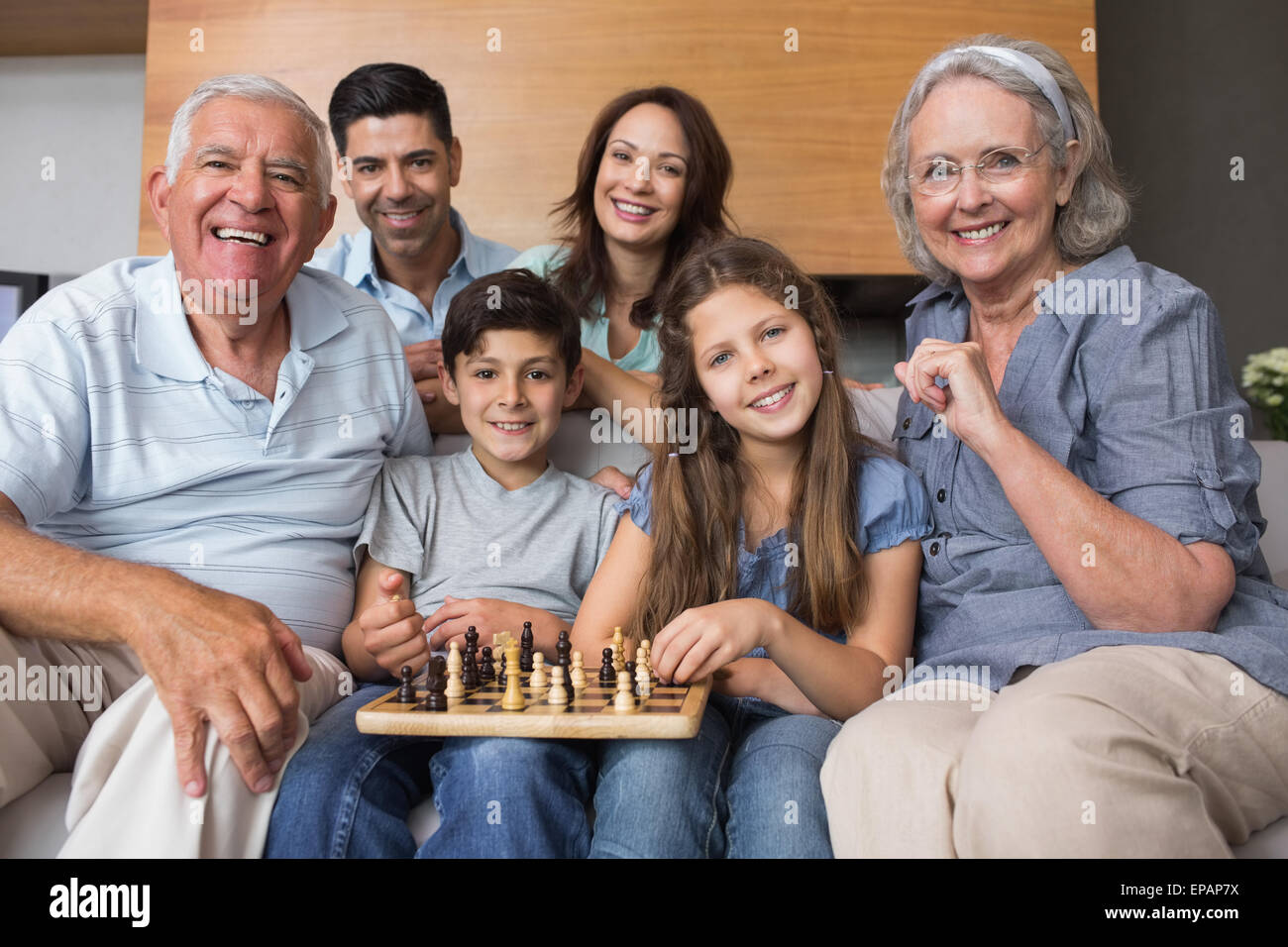 Portrait of happy extended family playing chess in living room Stock ...