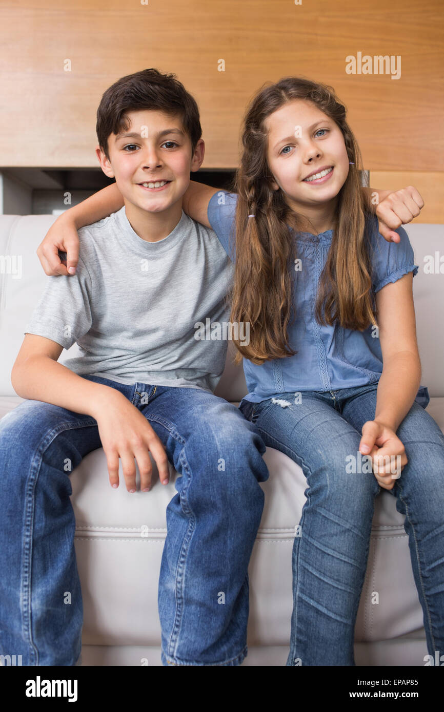 Portrait of smiling little siblings sitting in living room Stock Photo ...
