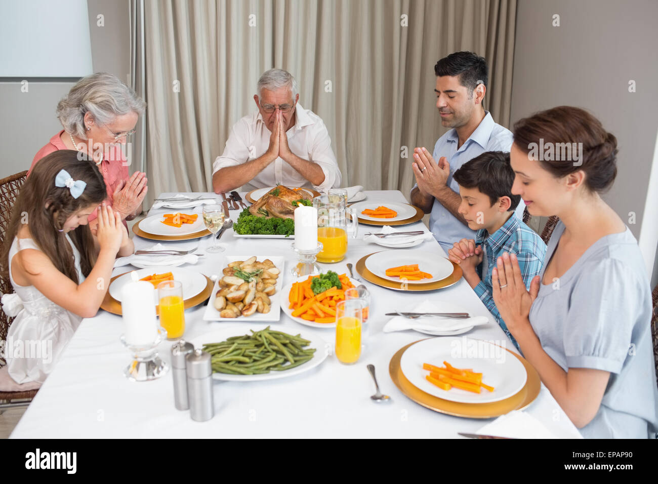 Family of six saying grace before meal at dining table Stock Photo - Alamy