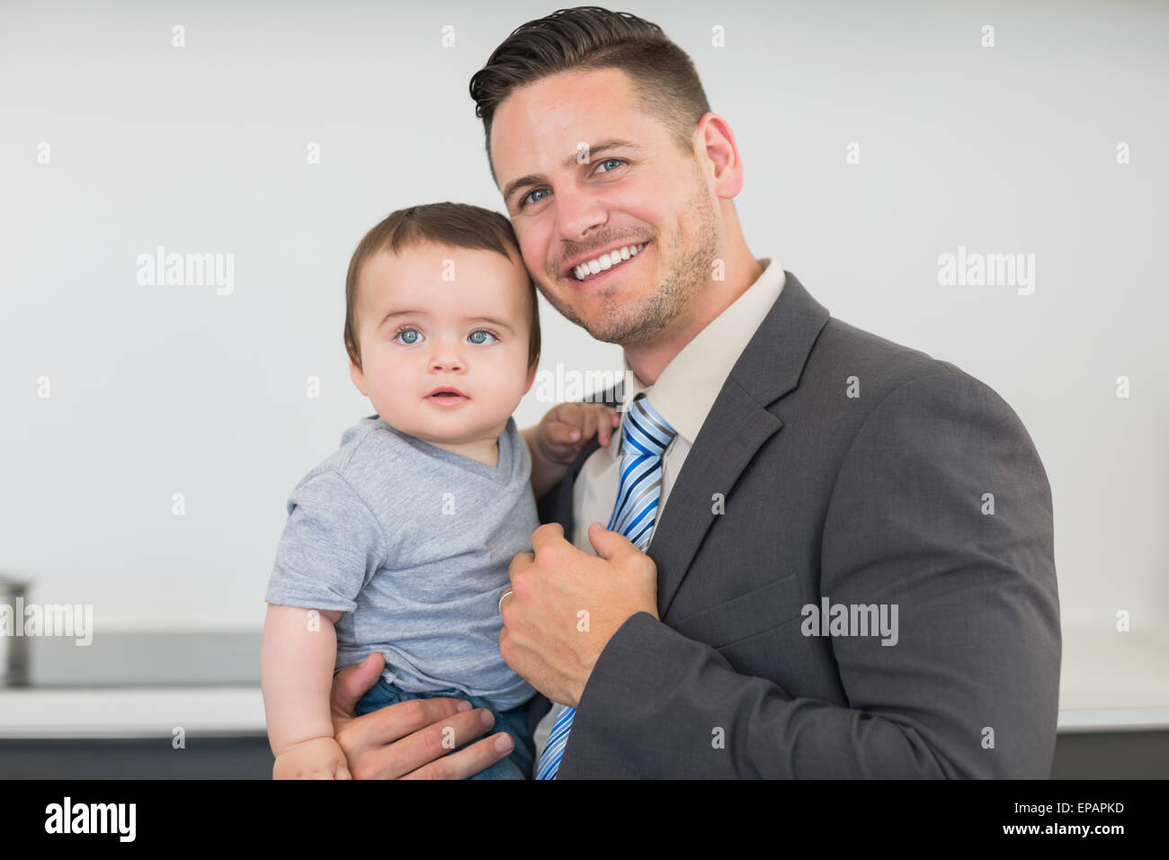 Smart businessman carrying baby boy in kitchen Stock Photo - Alamy