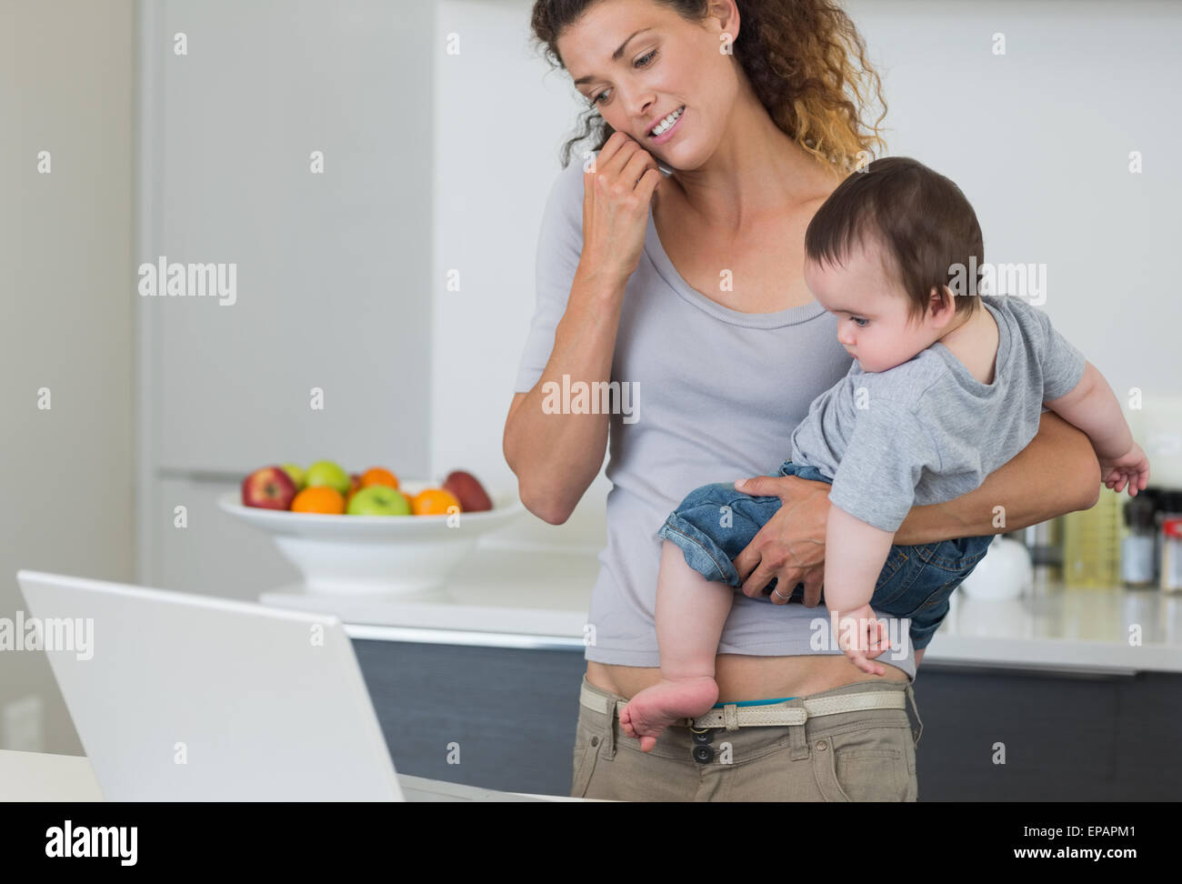 Mother answering cellphone while carrying baby Stock Photo - Alamy