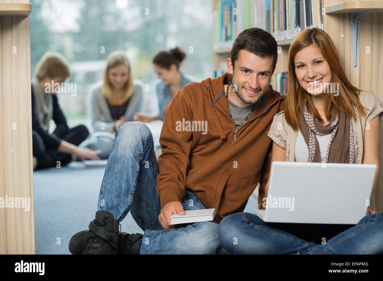 Smiling college students with laptop in library Stock Photo - Alamy