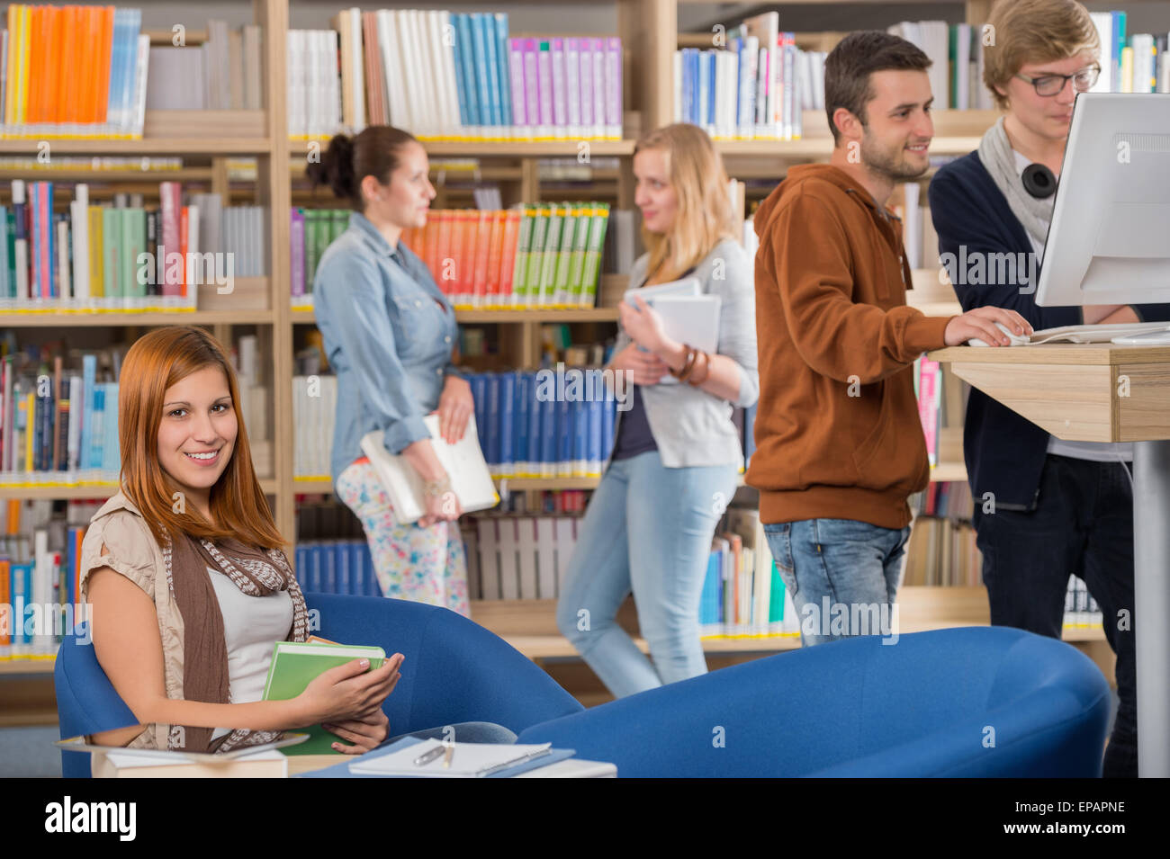 Smiling student in library with friends Stock Photo - Alamy