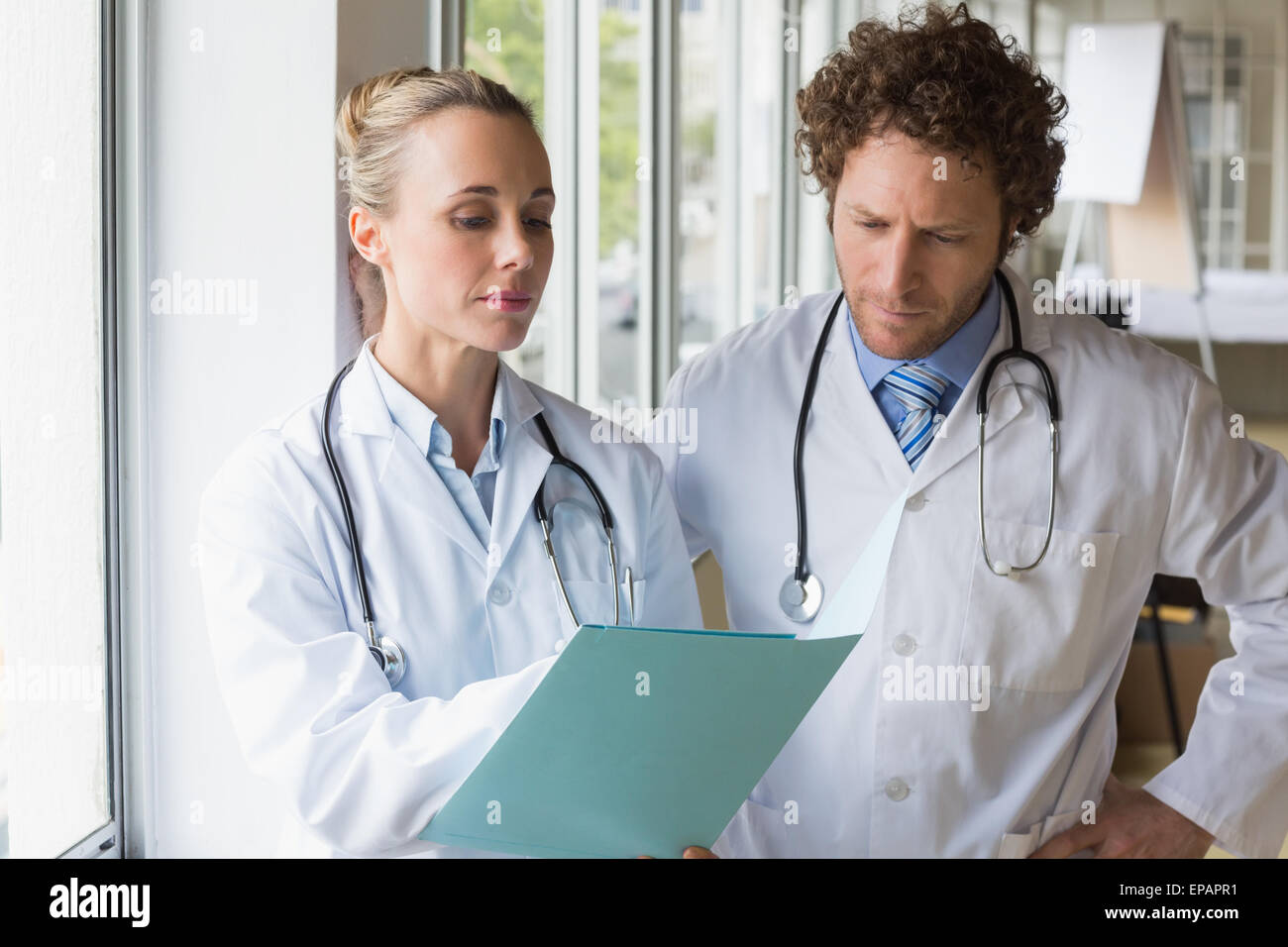 Doctors discussing over file Stock Photo - Alamy