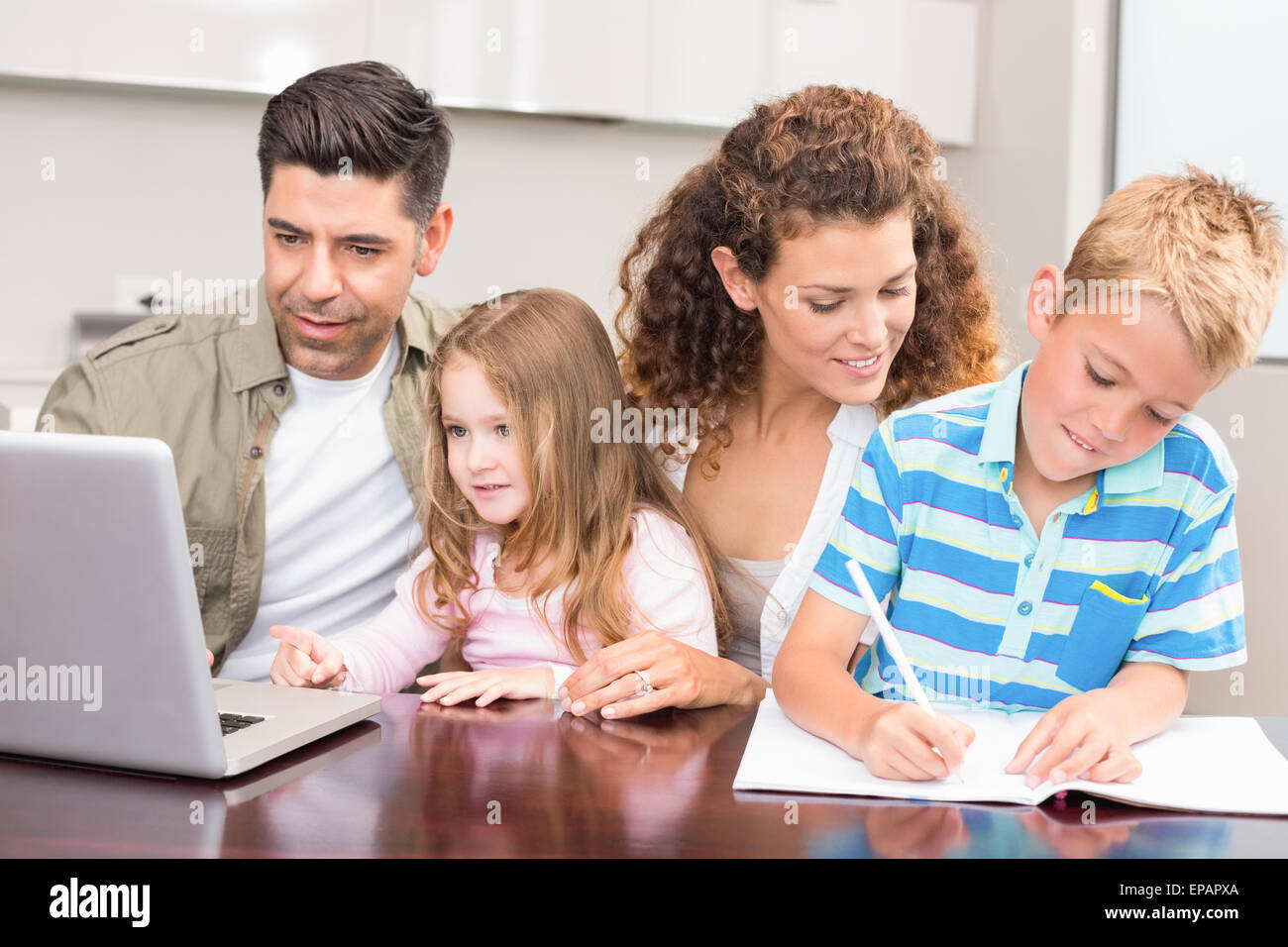 Cheerful parents colouring and using laptop with their children Stock ...