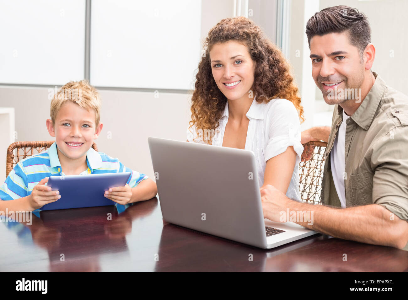 Happy parents sitting with son using tablet and laptop Stock Photo - Alamy