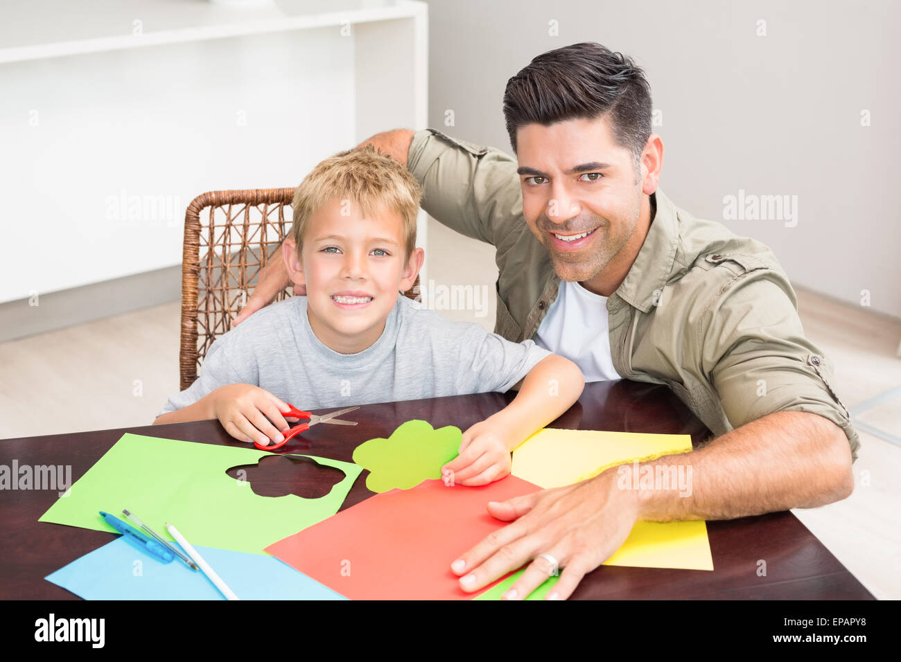 Happy father and son making paper shapes together at the table Stock ...