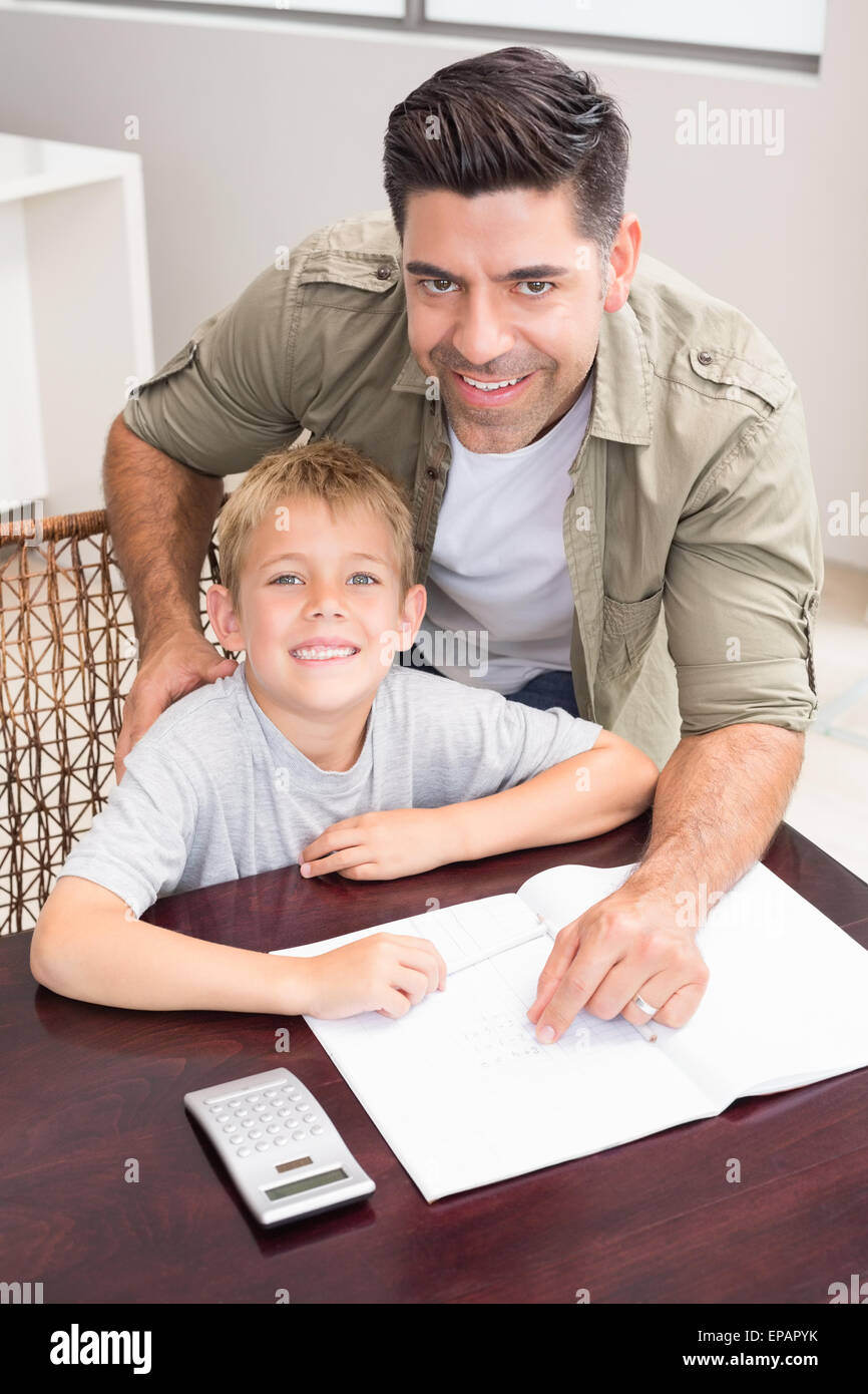 Cheerful father helping son with his math homework at table Stock Photo ...