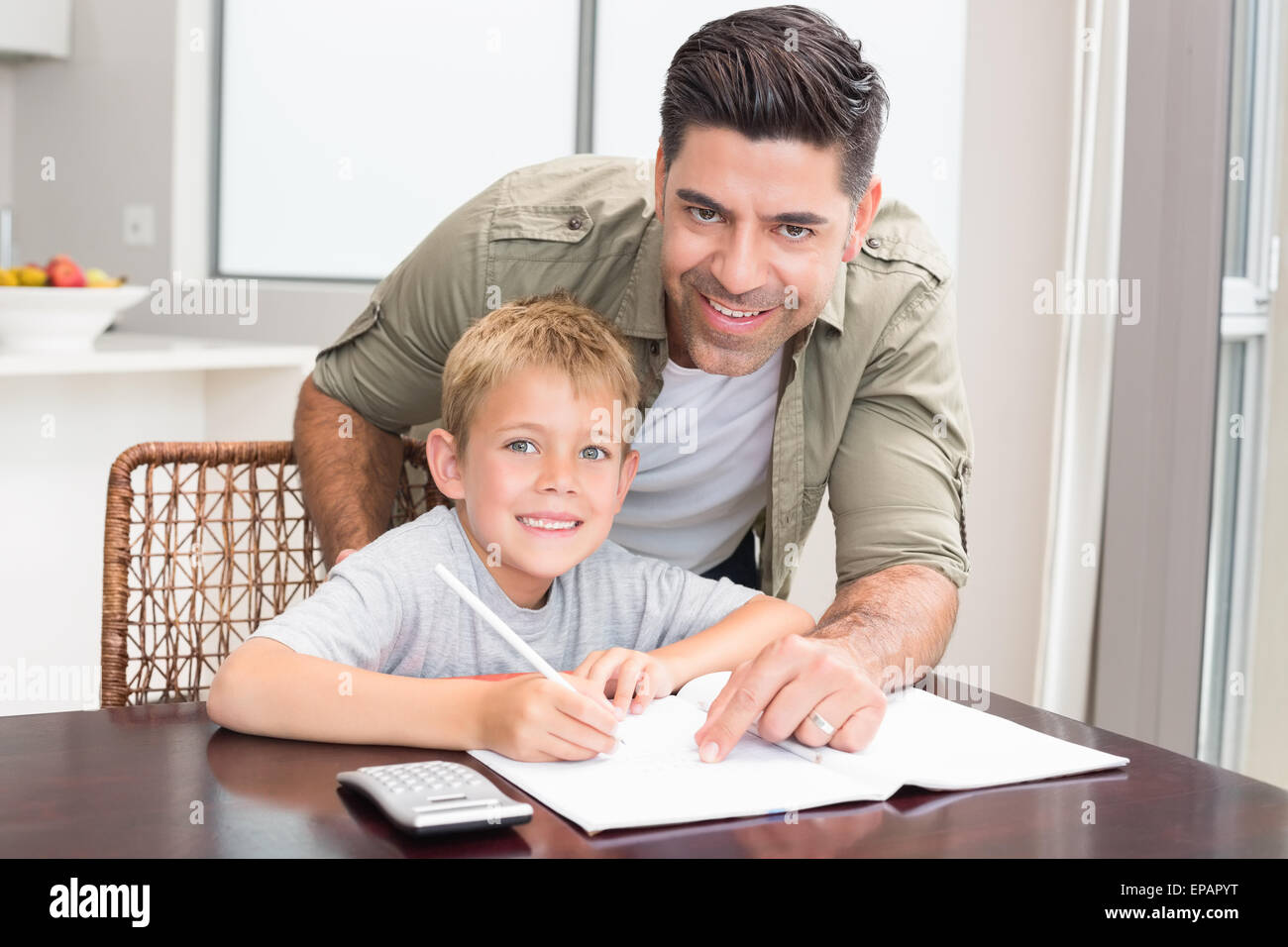 Cheerful father helping son with math homework at table Stock Photo - Alamy
