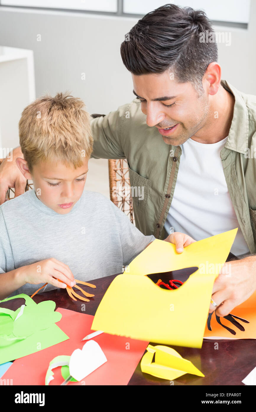 Little boy making paper shapes with father at the table Stock Photo - Alamy