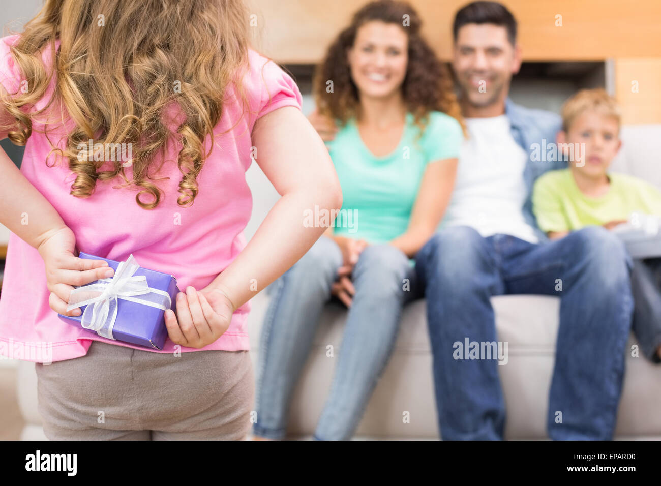 Little girl hiding present from her family behind back Stock Photo - Alamy