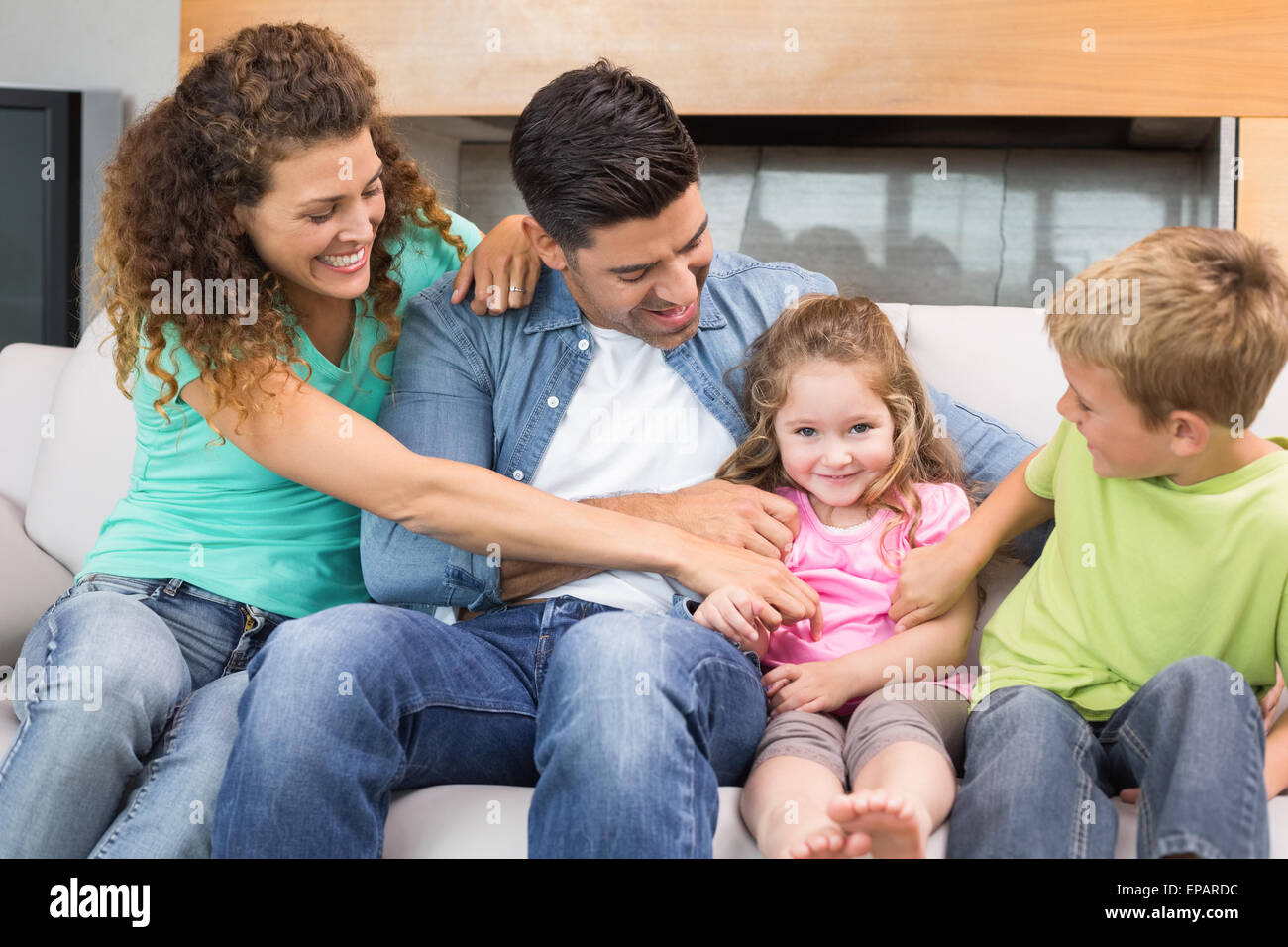 Cute family tickling little girl on the couch Stock Photo - Alamy