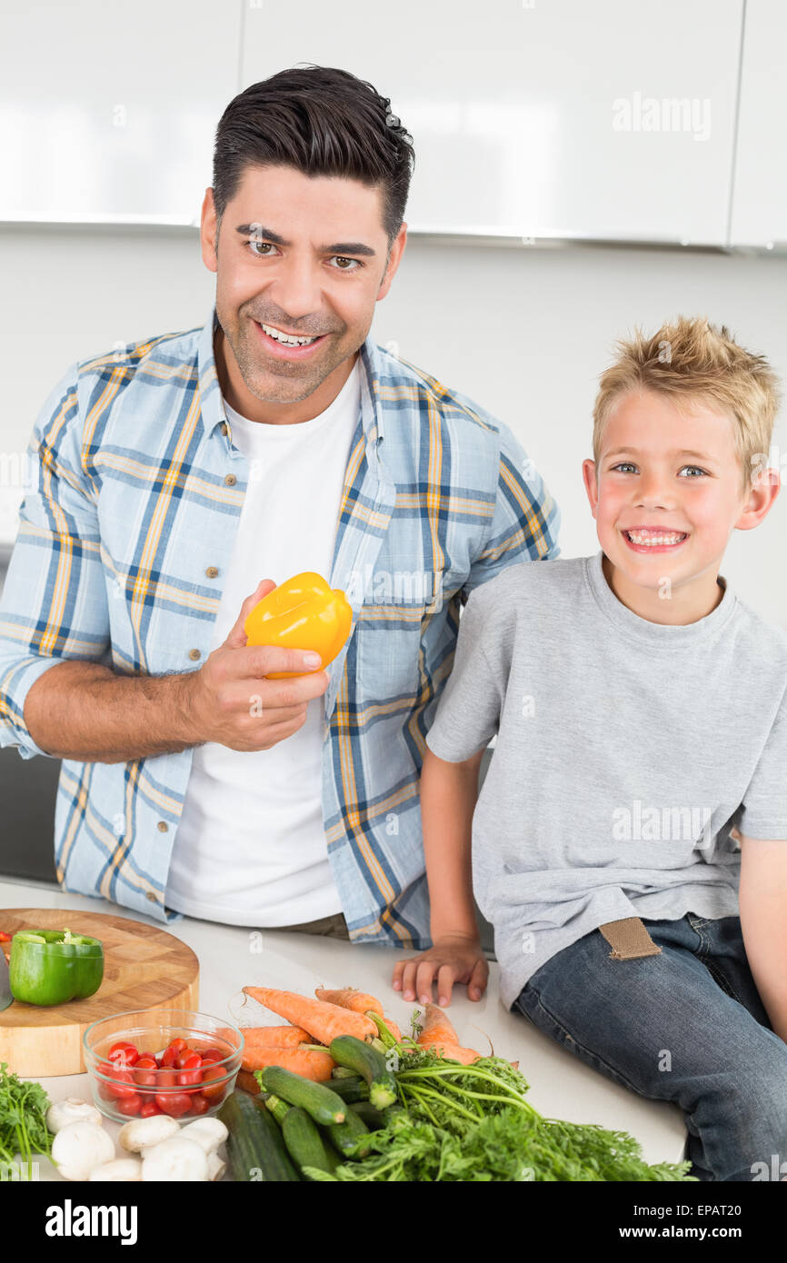 Smiling father holding a yellow pepper with his son Stock Photo - Alamy