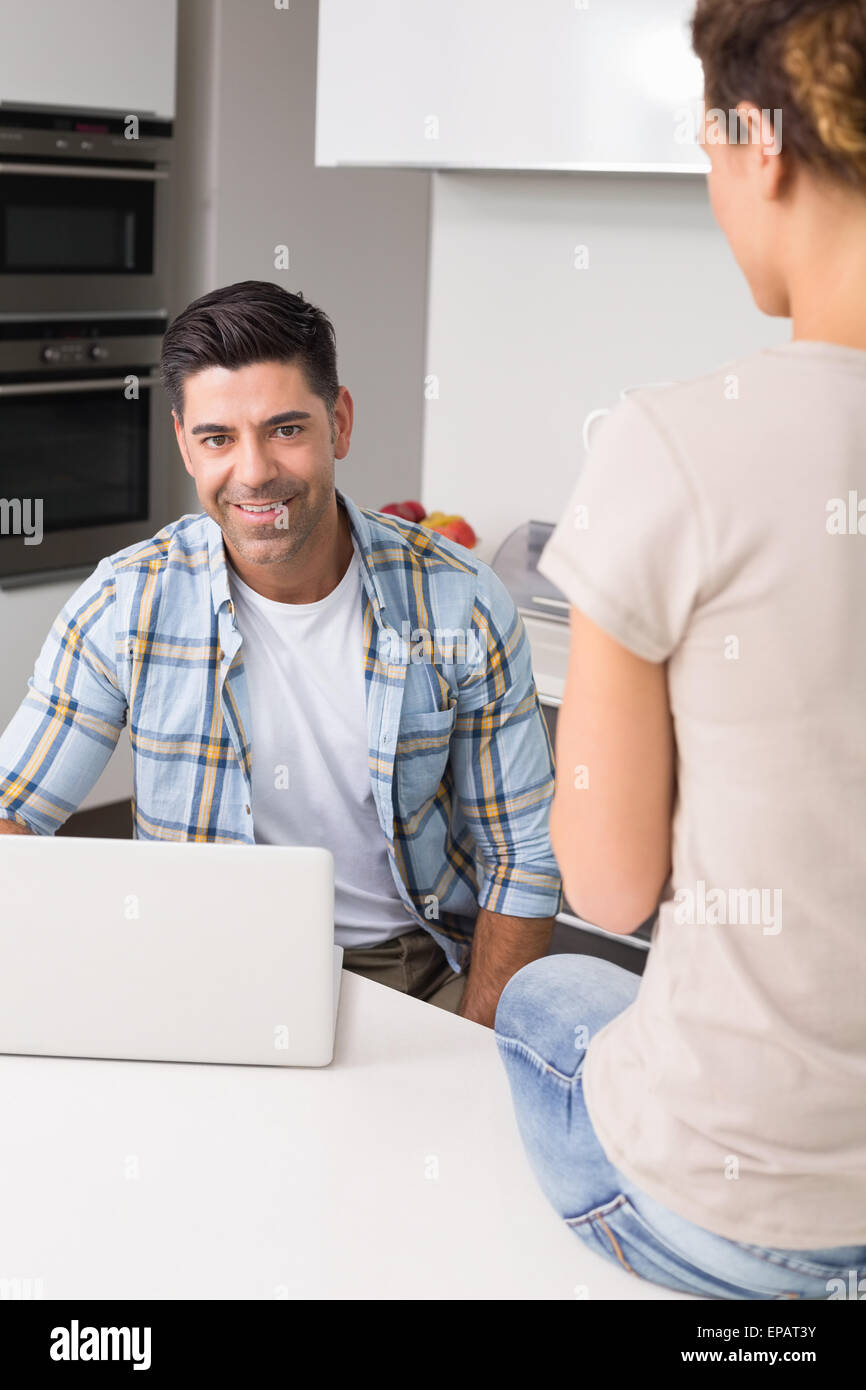 Cheerful man using laptop while partner sits on counter Stock Photo - Alamy