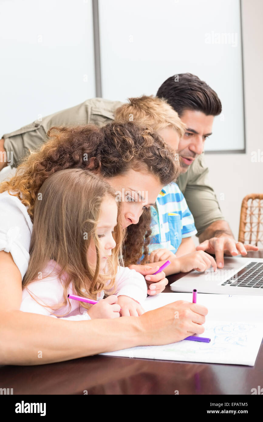 Attractive parents colouring and using laptop with their children Stock ...