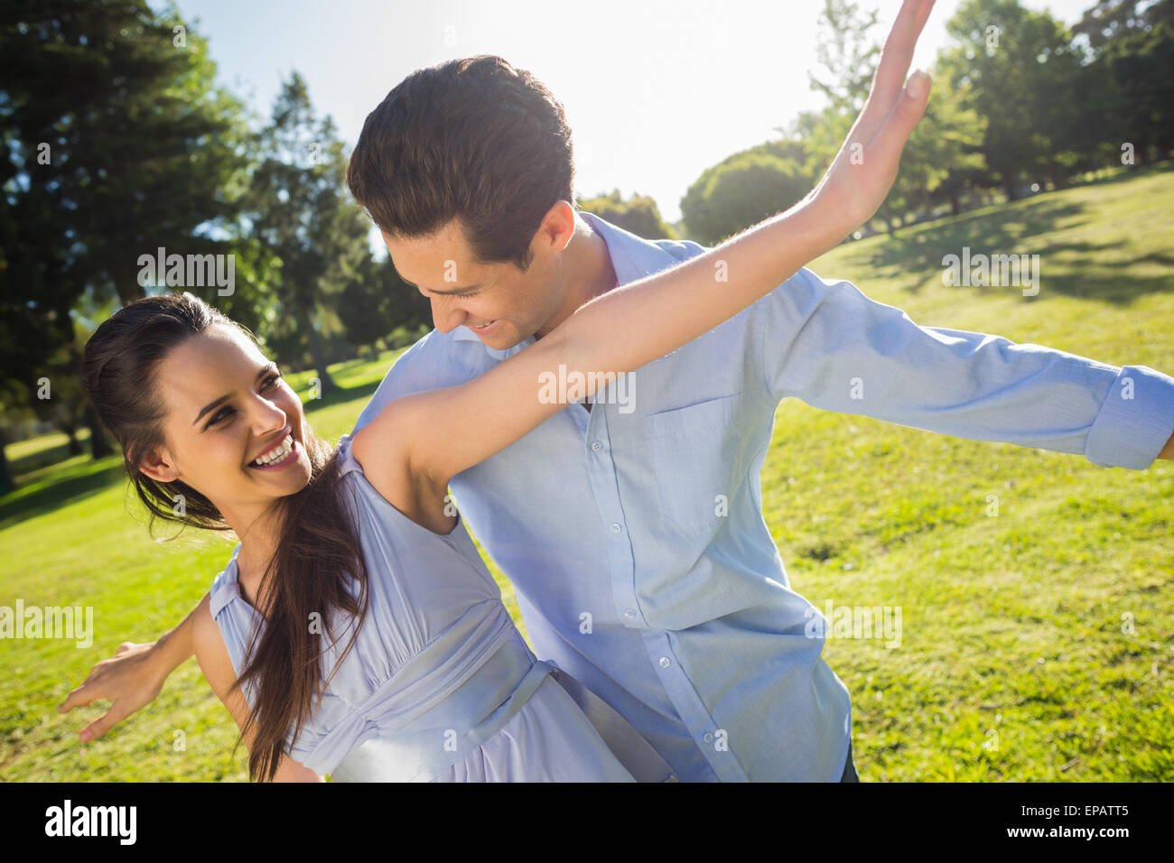 Happy young couple with arms outstretched at park Stock Photo - Alamy