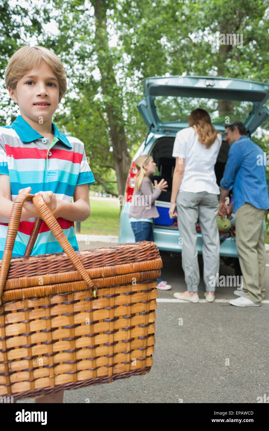 Boy with picnic basket while family in background at car trunk Stock ...