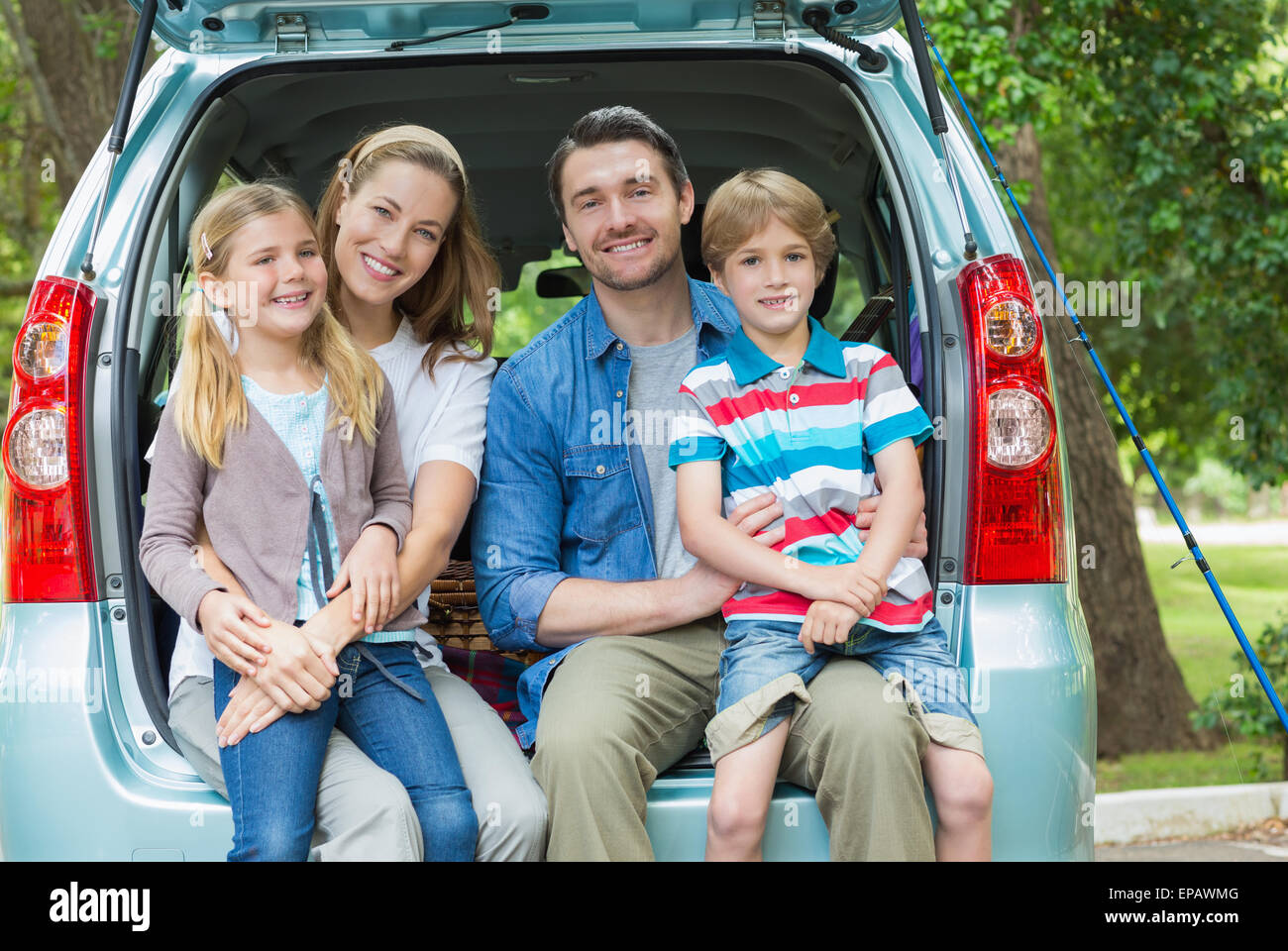 Portrait of happy family of four sitting in car trunk Stock Photo - Alamy