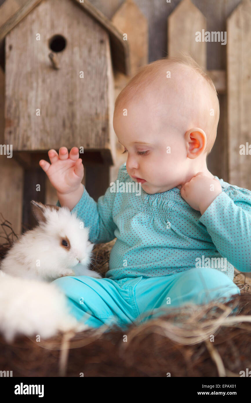 Happy little baby girl with a small white rabbit Stock Photo - Alamy