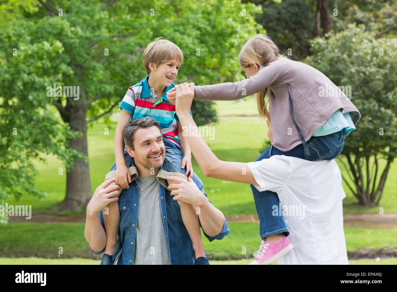 Parents carrying kids on shoulders at park Stock Photo - Alamy