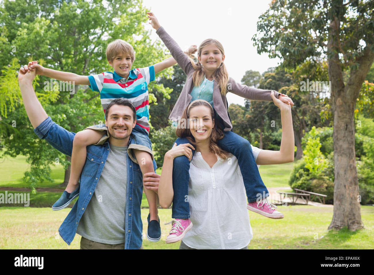 Parents carrying kids on shoulders at park Stock Photo - Alamy
