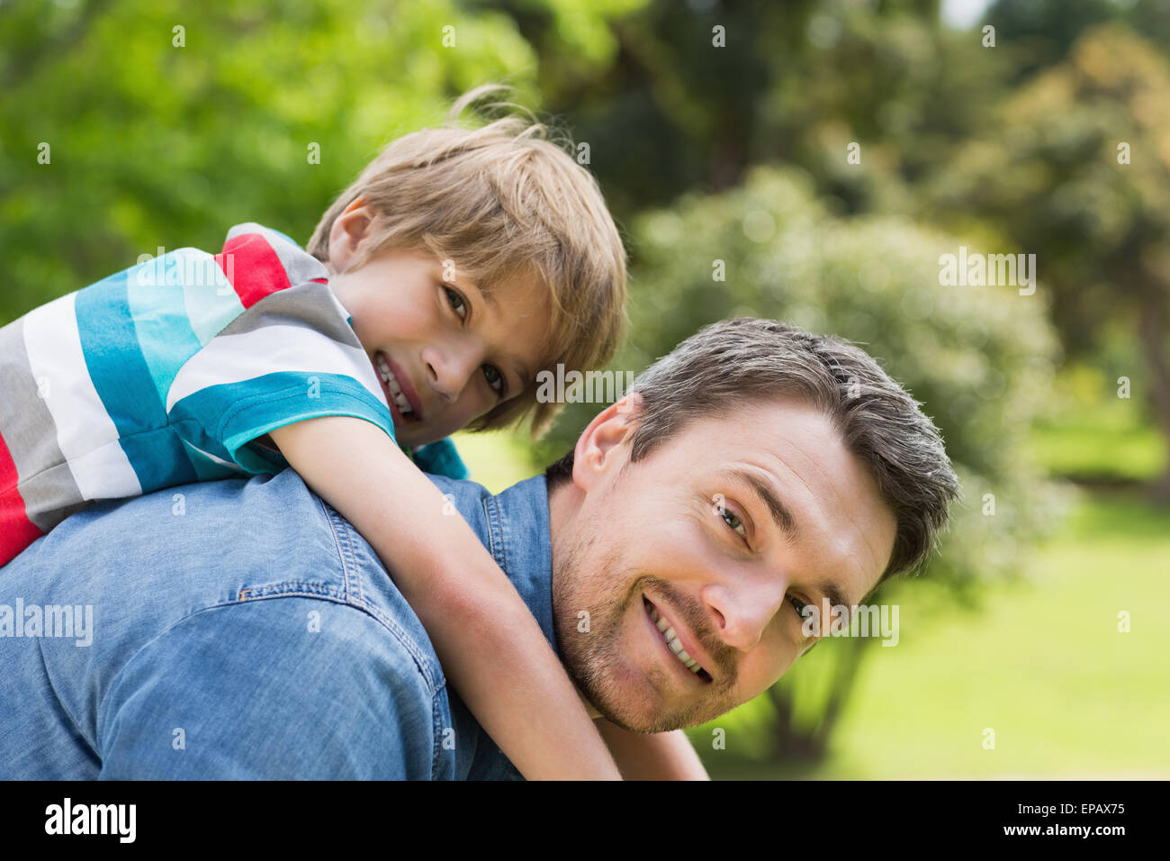 Father carrying young boy on back at park Stock Photo - Alamy