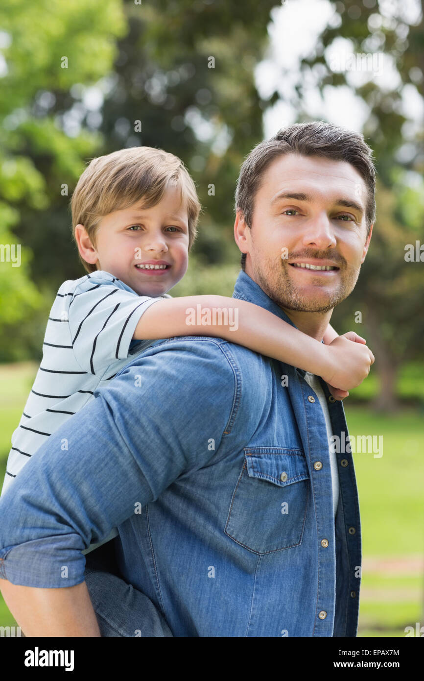 Portrait of father carrying boy on back at park Stock Photo - Alamy