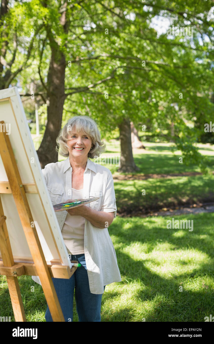 Smiling mature woman painting on canvas in park Stock Photo - Alamy