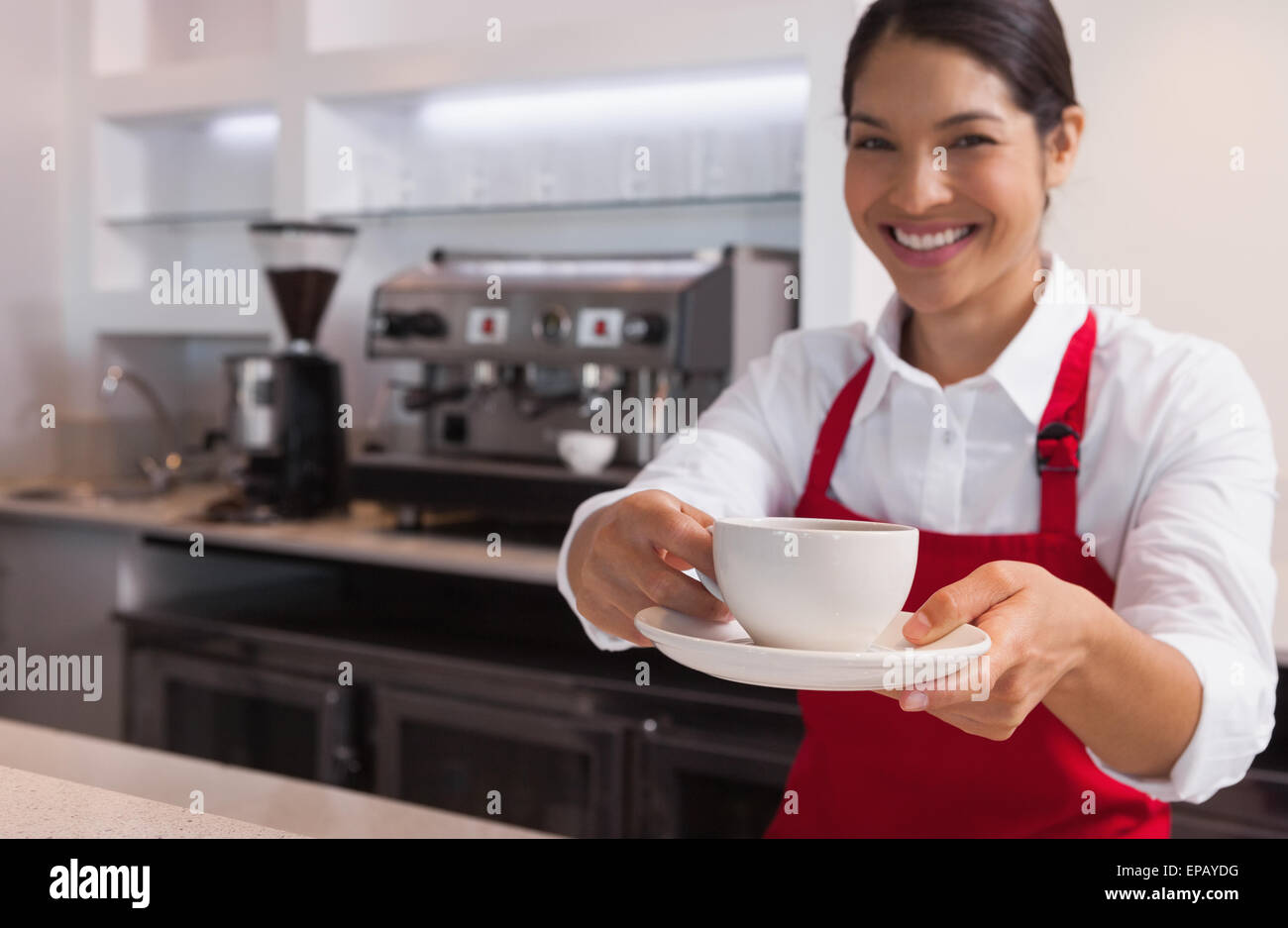 Happy young barista offering cup of coffee smiling at camera Stock ...