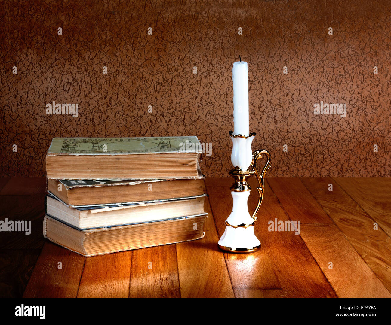 Old stack of books with candlestick and burning candle on the wooden ...