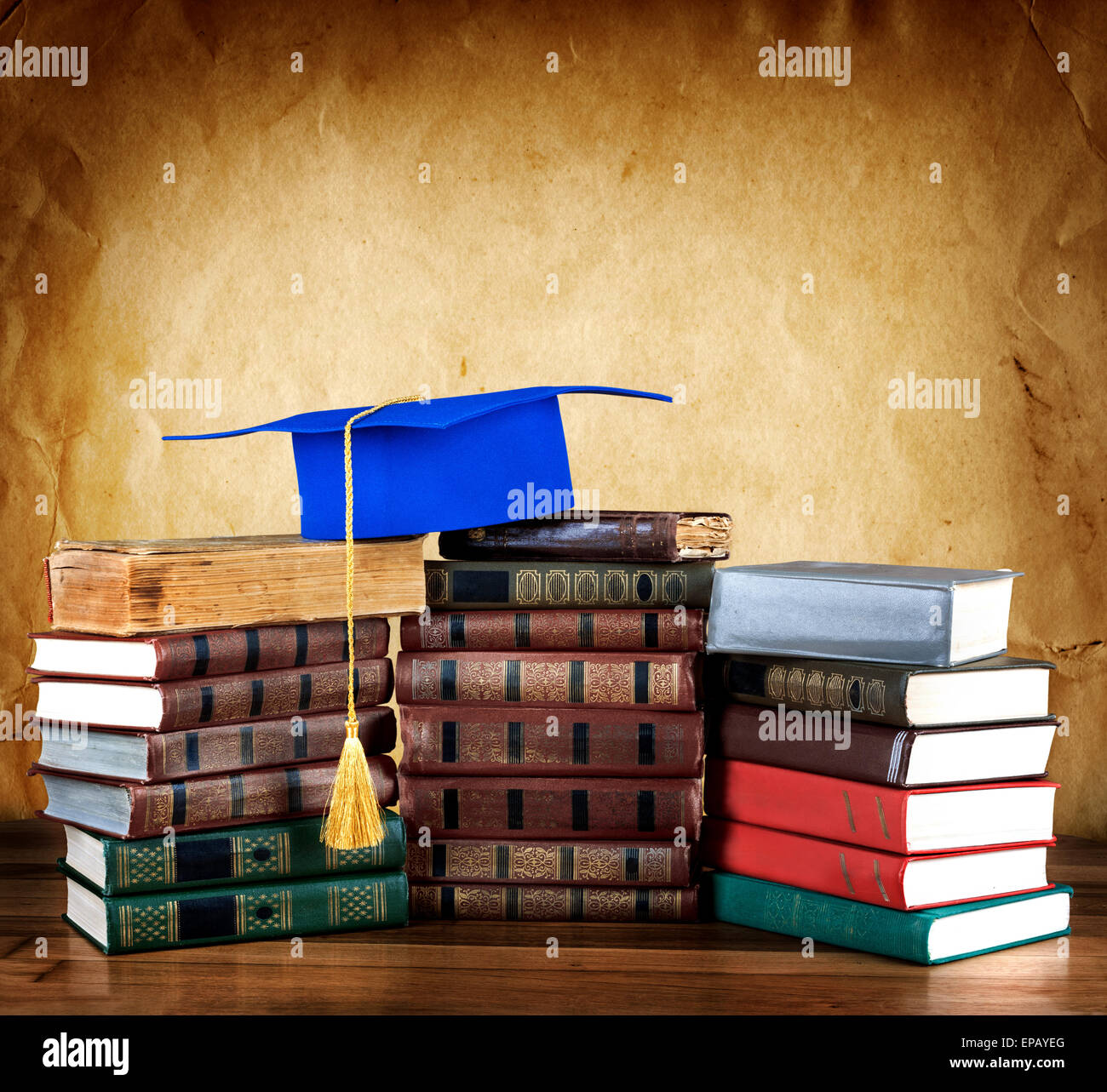 Graduation mortarboard on top of stack of books on abstract background ...