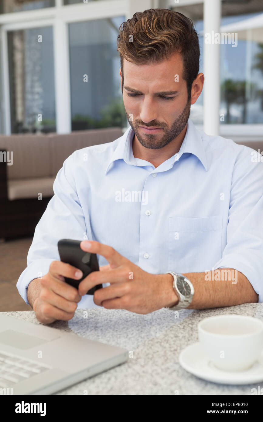 Frowning businessman sending a text at table in patio of restaurant Stock Photo - Alamy