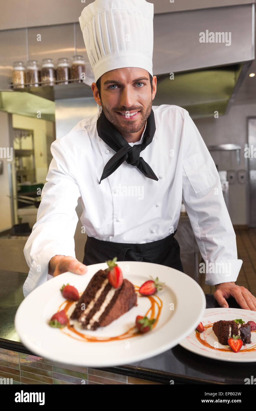 Happy chef offering chocolate cake to camera Stock Photo - Alamy