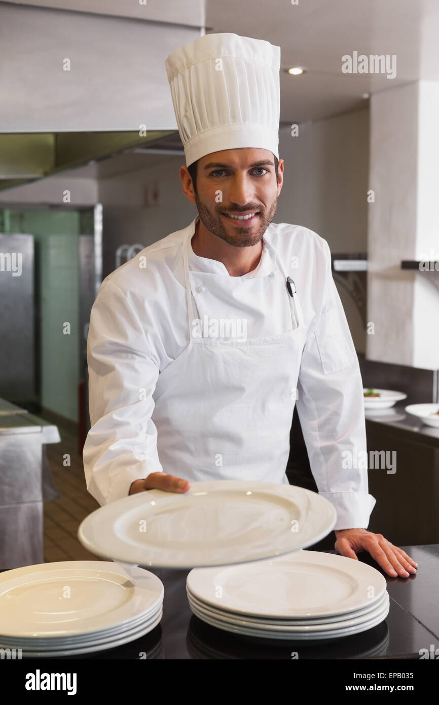 Happy head chef offering a plate smiling at camera Stock Photo - Alamy