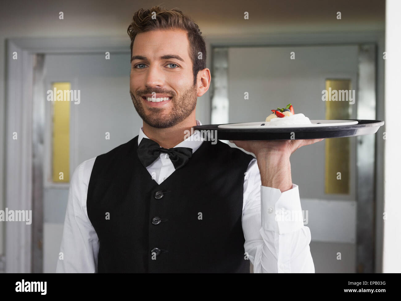 Smiling waiter holding tray with plate of dessert Stock Photo - Alamy