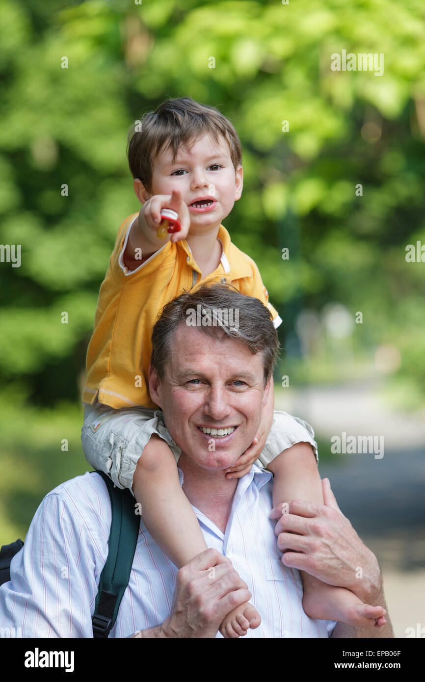 Young boy sitting on fathers shoulder Stock Photo - Alamy